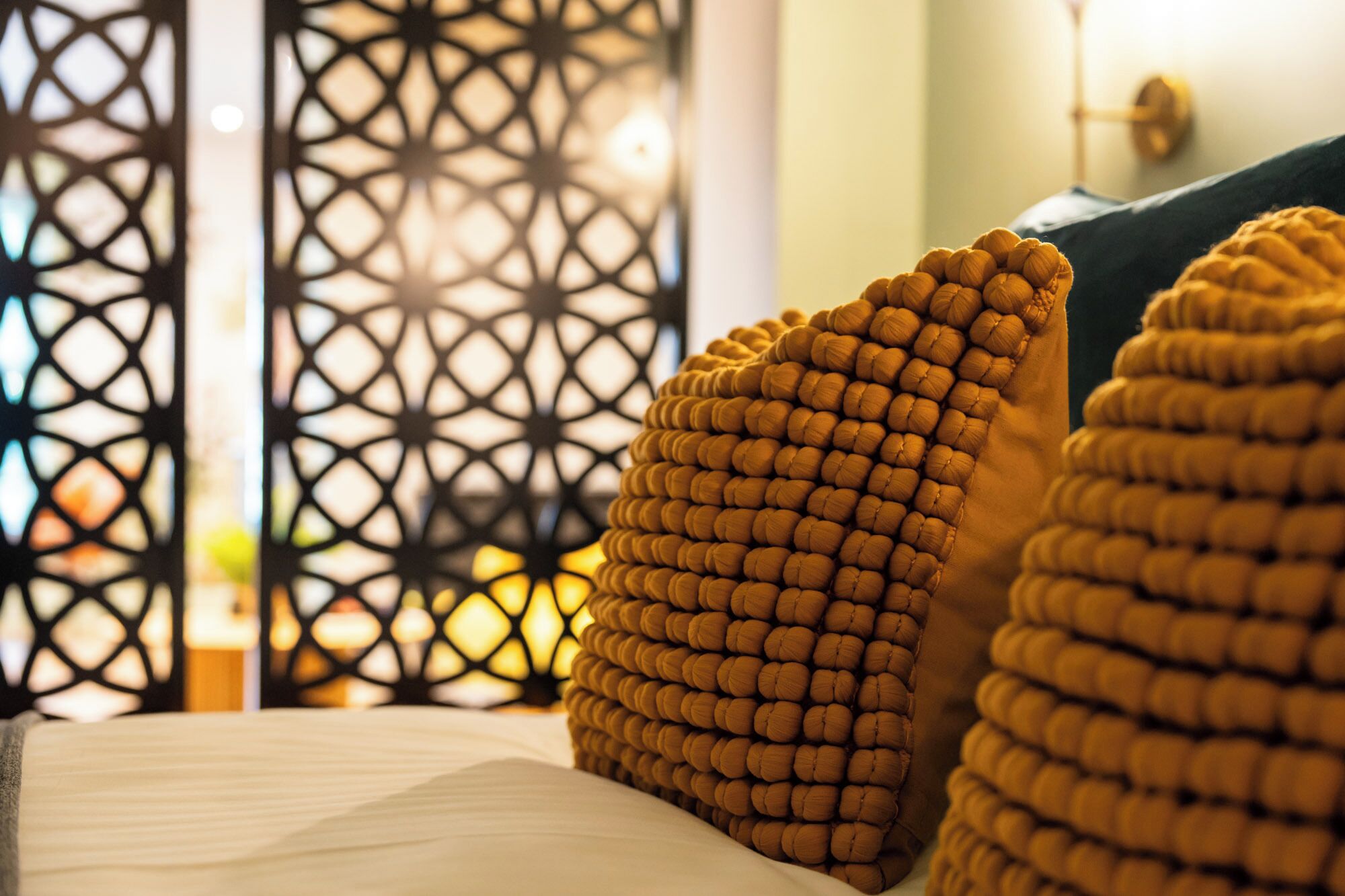 Uma cama com cabeceira estampada e um painel decorativo na parede ao fundo.