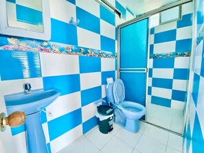 Casa de banho com azulejos azuis e brancos quadriculados, uma pia, sanita e um caixote de lixo.