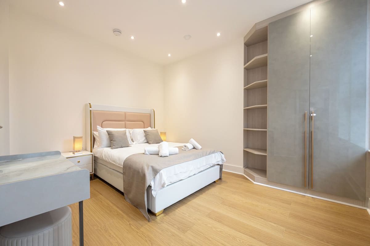 Quarto moderno com cama, mesa de cabeceira e guarda-roupa.