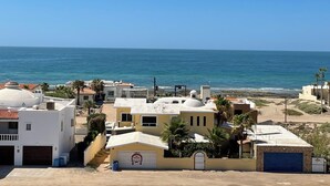 Uma área residencial costeira com casas, céu azul claro e o oceano ao fundo.