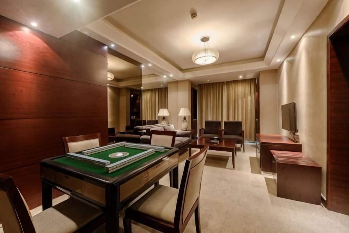 Quarto de hotel com mesa de bilhar, sofá, televisão e escrivaninha.