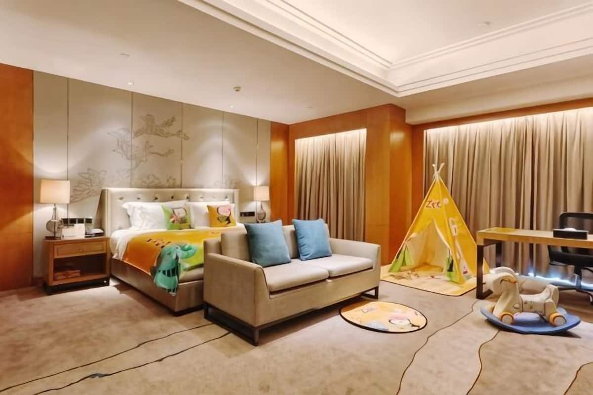 Quarto de hotel com cama, sofá, uma tenda e um balanço de cavalo.