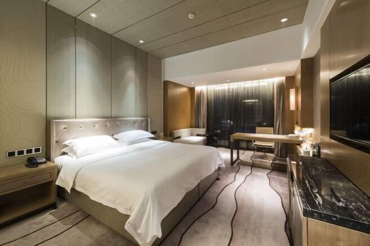 Quarto de hotel moderno com uma cama grande, uma escrivaninha e uma televisão.