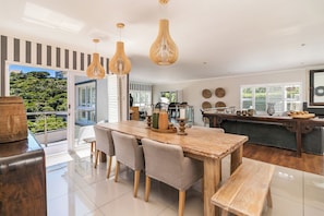 Uma cozinha moderna com mesa de madeira, cadeiras e luminárias pendentes.