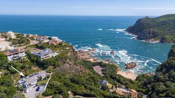 Zona residencial costeira com casas, praia e falésias rochosas.