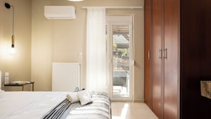 Quarto com cama, mesa de cabeceira, guarda-roupa e porta de vidro deslizante para uma varanda.