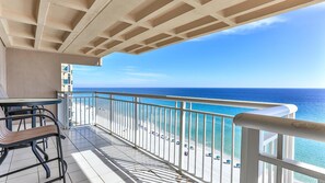 Uma varanda com vista para o oceano, uma mesa e cadeiras.