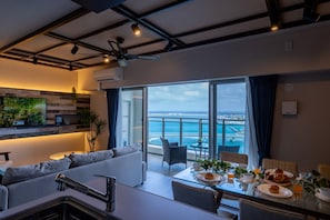 Uma sala de estar moderna com sofá, mesa de jantar e vista para o oceano.