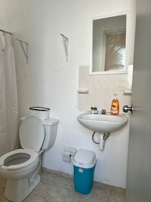 Casa de banho com sanita, bidé, lavatório e lixeira.