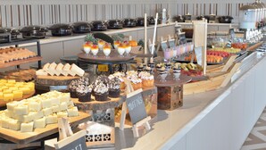 Buffet com diversos alimentos, incluindo doces, frutas e sobremesas.