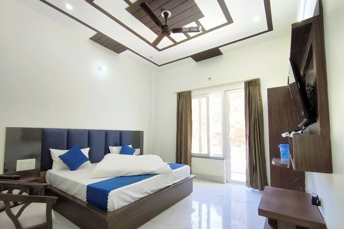 Quarto moderno com uma cama grande, escrivaninha e ventilador de teto.