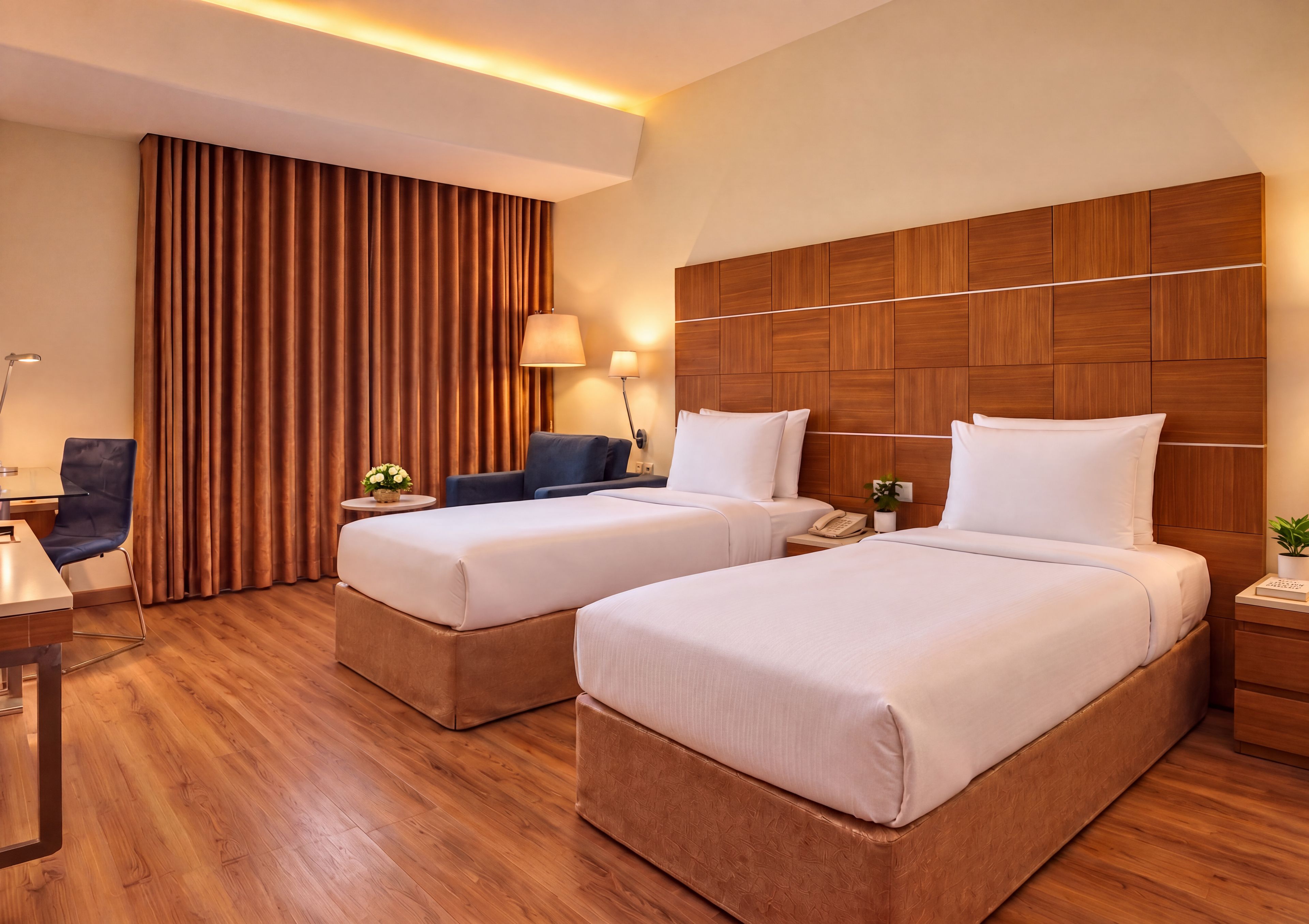 Quarto de hotel com duas camas, uma escrivaninha, uma cadeira, um abajur e uma cortina.