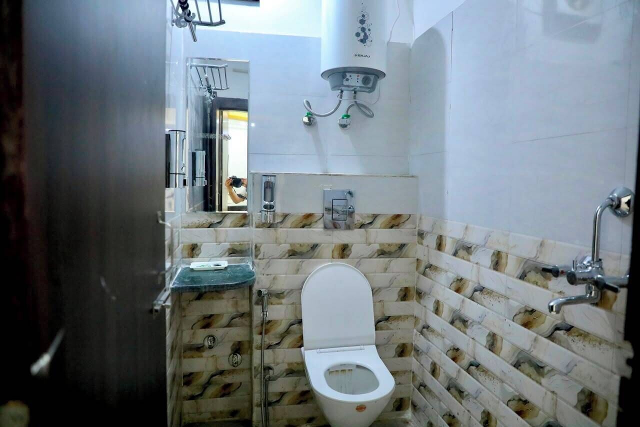 Casa de banho com sanita, secador de mãos e lavatório fixo na parede.