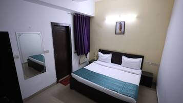 Quarto com cama, espelho, porta, luminária na parede e um quadro.