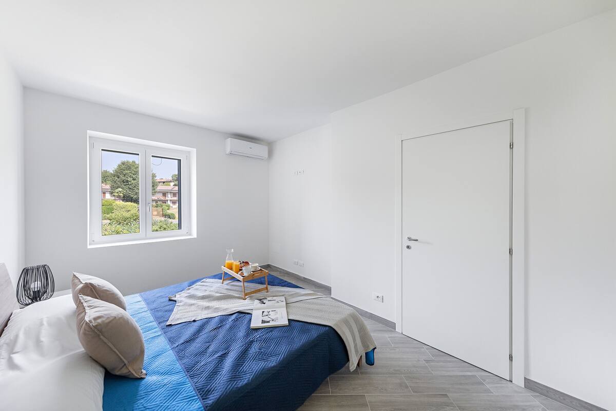 Um quarto com uma cama, uma janela e uma porta.