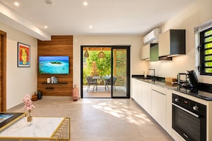 Cozinha moderna com uma televisão grande, área de refeições com vista e porta de vidro deslizante para área externa.