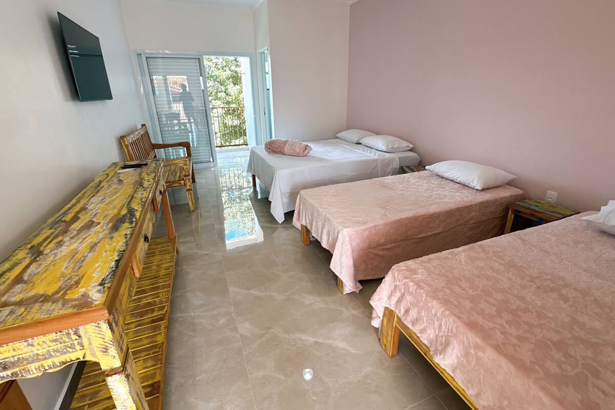 Quarto de hotel com duas camas, uma escrivaninha e uma cadeira.