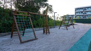 Um parquinho com balanços e uma estrutura de escalada.