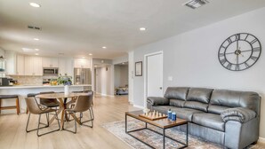Uma sala de estar moderna com um sofá de couro, uma mesa de centro e uma área de jantar com uma mesa e cadeiras de madeira.