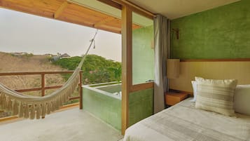 Quarto com cama, rede, vista do exterior e parede verde.