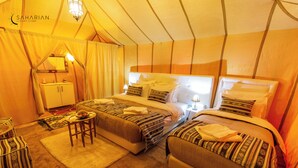 Uma tenda luxuosa com duas camas, uma mesa pequena e um armário.