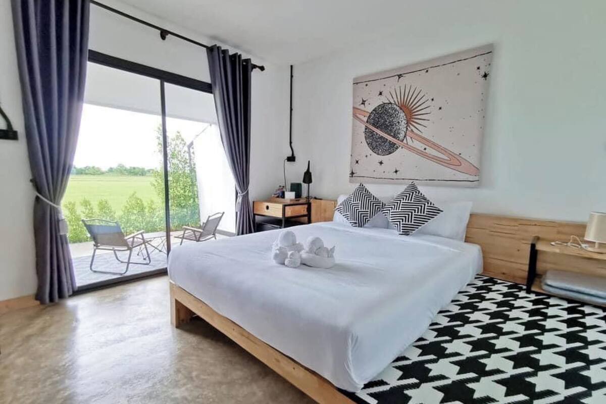 Quarto com cama grande, vista para o exterior e um quadro na parede.