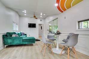 Uma sala de estar moderna com um sofá verde, cadeiras cinzas e uma mesa de centro branca.
