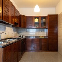 Uma cozinha compacta com armários de madeira, uma pia de aço inoxidável e um forno embutido.