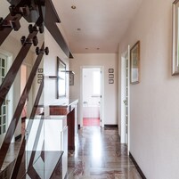 Um interior moderno com escadas, um corredor que leva a uma porta e quadros nas paredes.