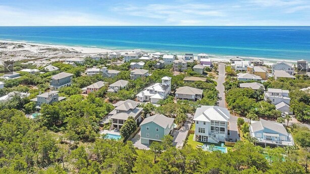 Uma área residencial costeira com casas, uma praia e céu azul límpido.