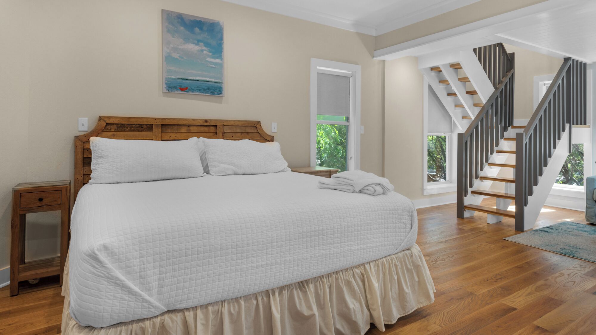 Quarto com uma cama grande, cabeceira de madeira e um quadro de um barco na parede.