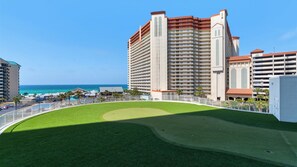 Um hotel moderno com várias varandas, um gramado bem cuidado e vista para o oceano.
