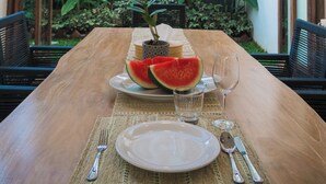 Uma mesa de jantar com um jogo de toalha, pratos, talheres, um copo e uma fatia de melancia.
