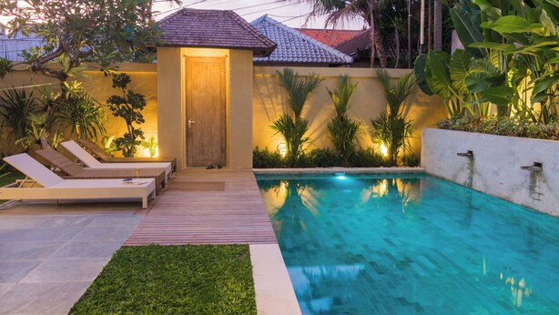 Piscina com deck de madeira, espreguiçadeiras e uma pequena porta.
