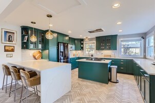 Uma cozinha moderna com armários verde-água, uma ilha grande e um chão de madeira em padrão herringbone.