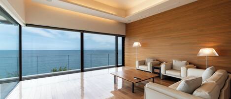 Uma sala de estar moderna com uma grande janela com vista para o mar, uma parede de madeira e um conjunto de sofá.