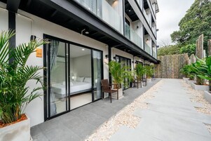 Um edifício moderno com fachada de vidro, mesas ao ar livre e plantas em vasos.