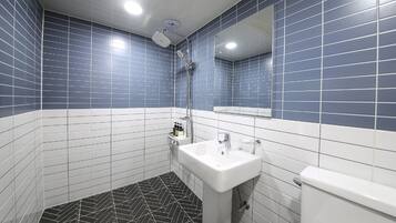 Um banheiro com paredes revestidas de azulejos azuis e brancos, uma pia branca e um chão com padrão preto e branco.