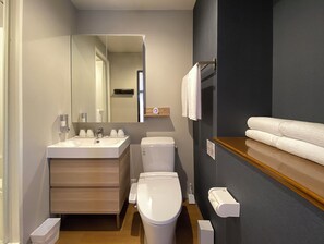 Uma casa de banho moderna com lavatório, sanita e espelho.