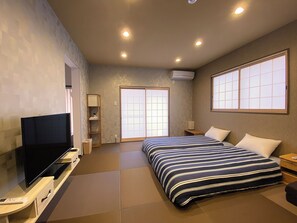 Quarto de hotel com uma cama, televisão, prateleira e janela.