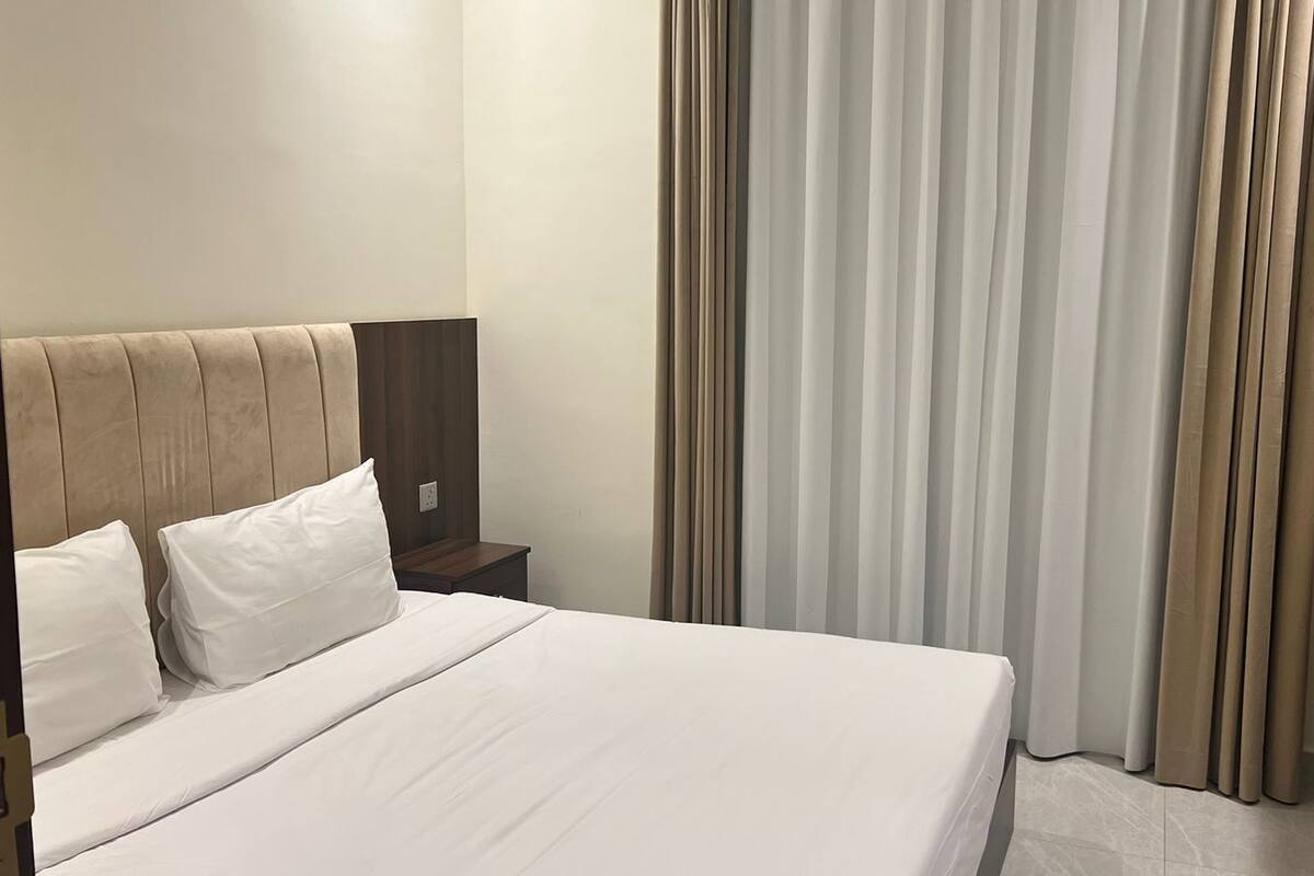 Quarto de hotel com uma cama, mesa de cabeceira e guarda-roupa.