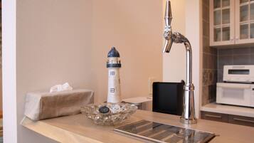 Uma cozinha com uma torneira moderna, um farol decorativo e um micro-ondas.
