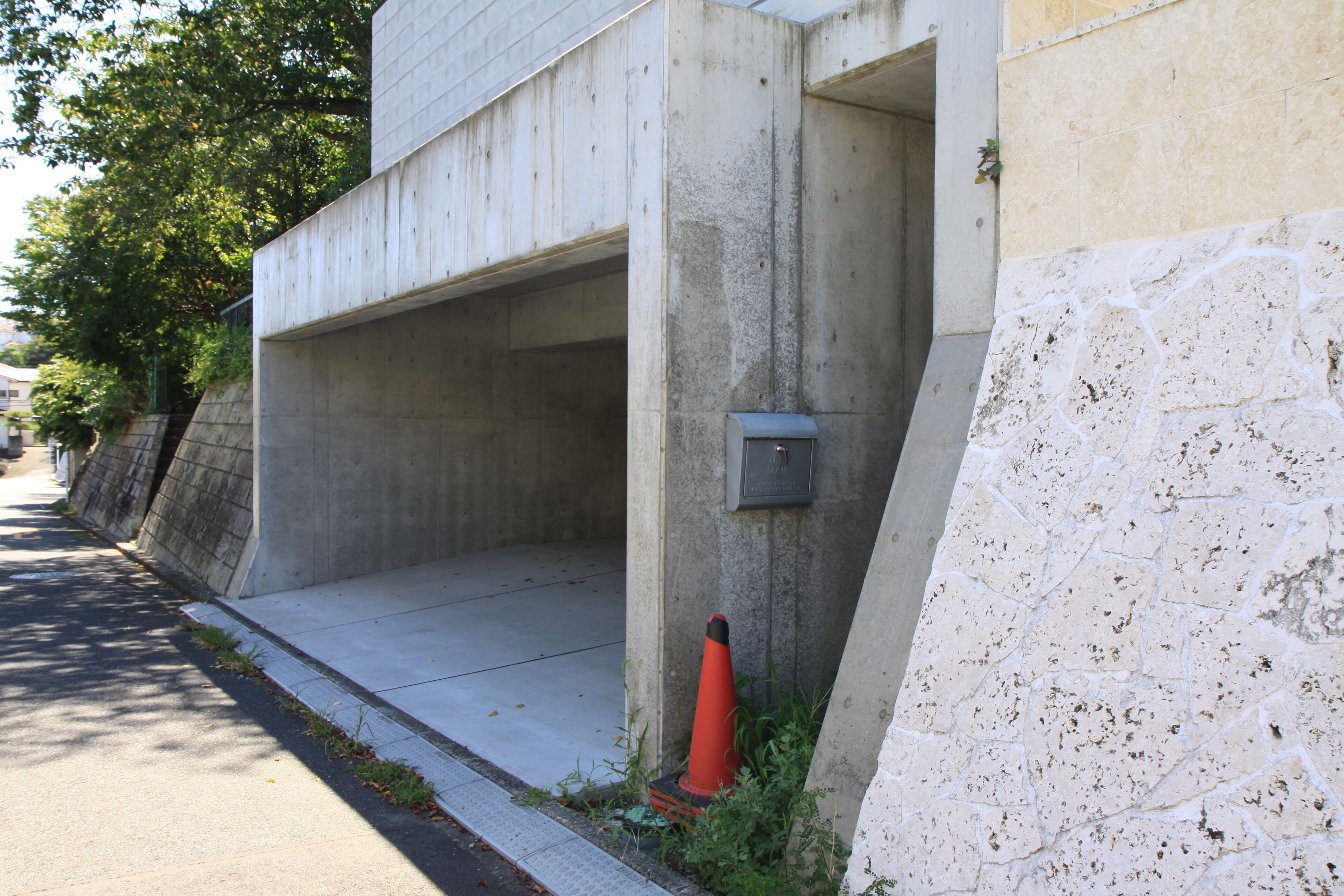 Uma estrutura de concreto com parede de pedra, calçada e um cone de trânsito.