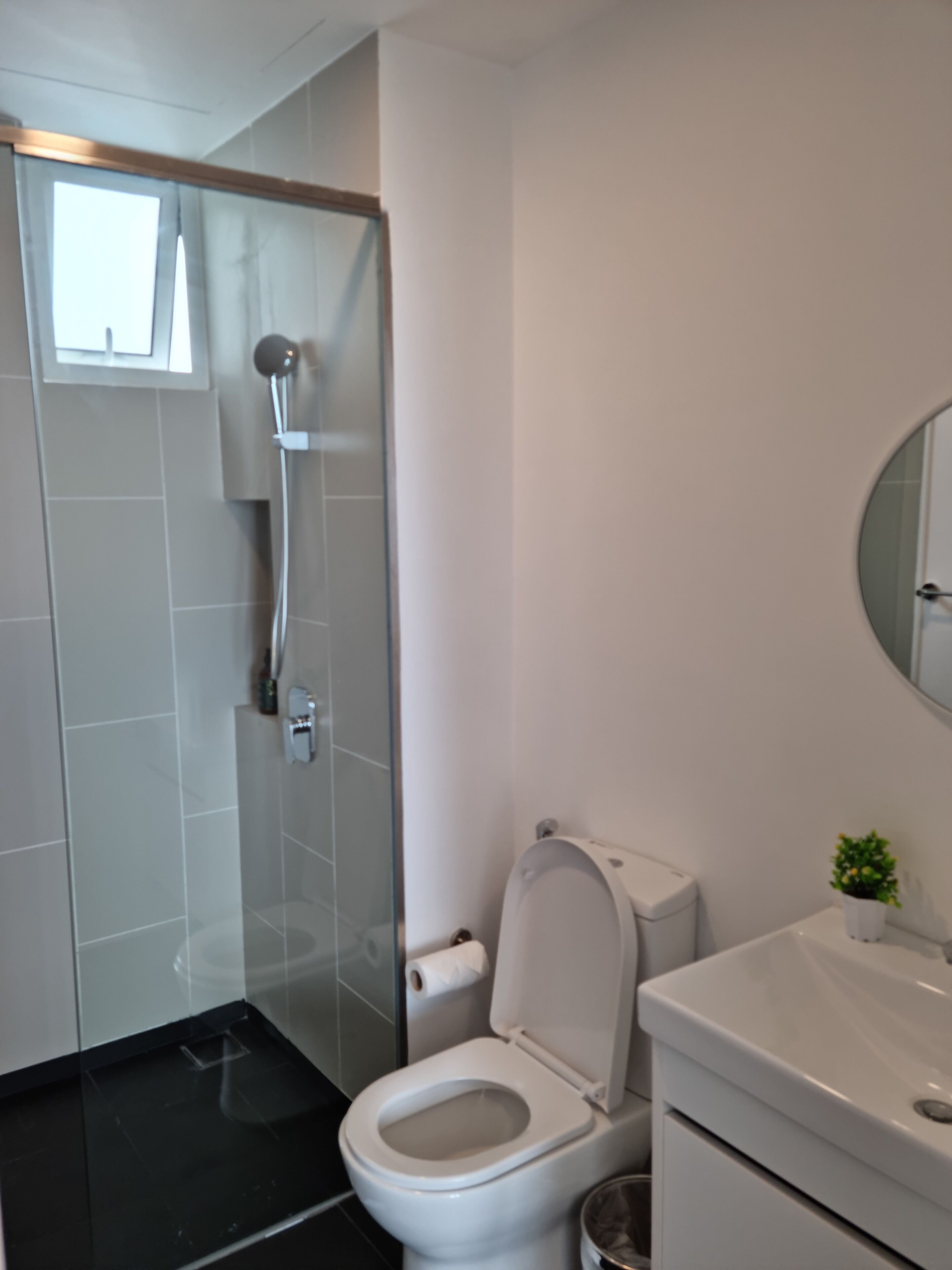 Uma casa de banho moderna com sanita, lavatório e chuveiro.
