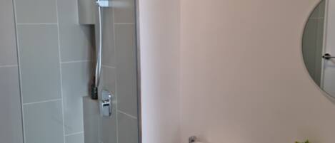 Uma casa de banho moderna com sanita, lavatório e chuveiro.