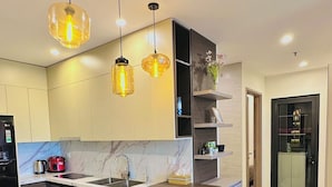 Uma cozinha moderna com ilha central, luminárias pendentes e forno embutido.