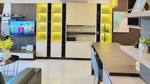 Uma cozinha moderna com eletrodomésticos embutidos, um espaço de jantar com banco e uma TV exibindo um programa.