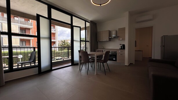 Um apartamento moderno com área de refeições, cozinha e varanda com vista para o bairro.