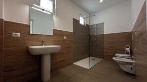 Uma casa de banho moderna com lavatório suspenso, cabine de duche com vidro e sanita.