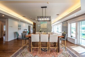 Uma sala de jantar espaçosa com uma grande mesa de madeira, quatro cadeiras e um lustre moderno.